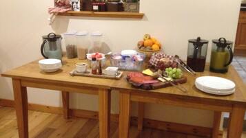 Uma mesa de madeira com diversos alimentos, acompanhamentos e bebidas, sugerindo um café da manhã ou um lanche.