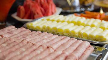 Buffet com diversos pratos, incluindo carnes enroladas e legumes.