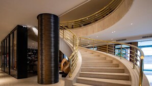 Uma escadaria imponente com design curvo e balaústres dourados, levando a um andar superior.
