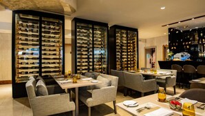 Um restaurante com várias mesas e cadeiras, uma adega e um espaço de bar.
