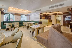 Interior moderno de restaurante com assentos em verde, cadeiras bege e uma mesa de jantar central.