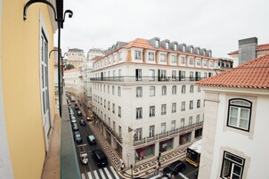 Um edifício com vários andares, varandas, uma passarela para pedestres e vista para a rua.