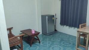 Um quarto pequeno com uma mesa de madeira, um refrigerador e um chão estampado.