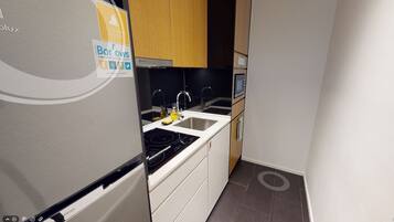 Uma cozinha compacta com forno embutido, pia e geladeira.