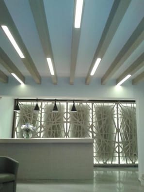 Uma área de recepção moderna com parede de padrão geométrico, um balcão de atendimento e iluminação pendente.
