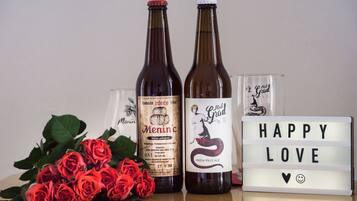 Duas garrafas de cerveja, um buquê de rosas vermelhas e uma caixa de luz com a mensagem 'HAPPY LOVE'.