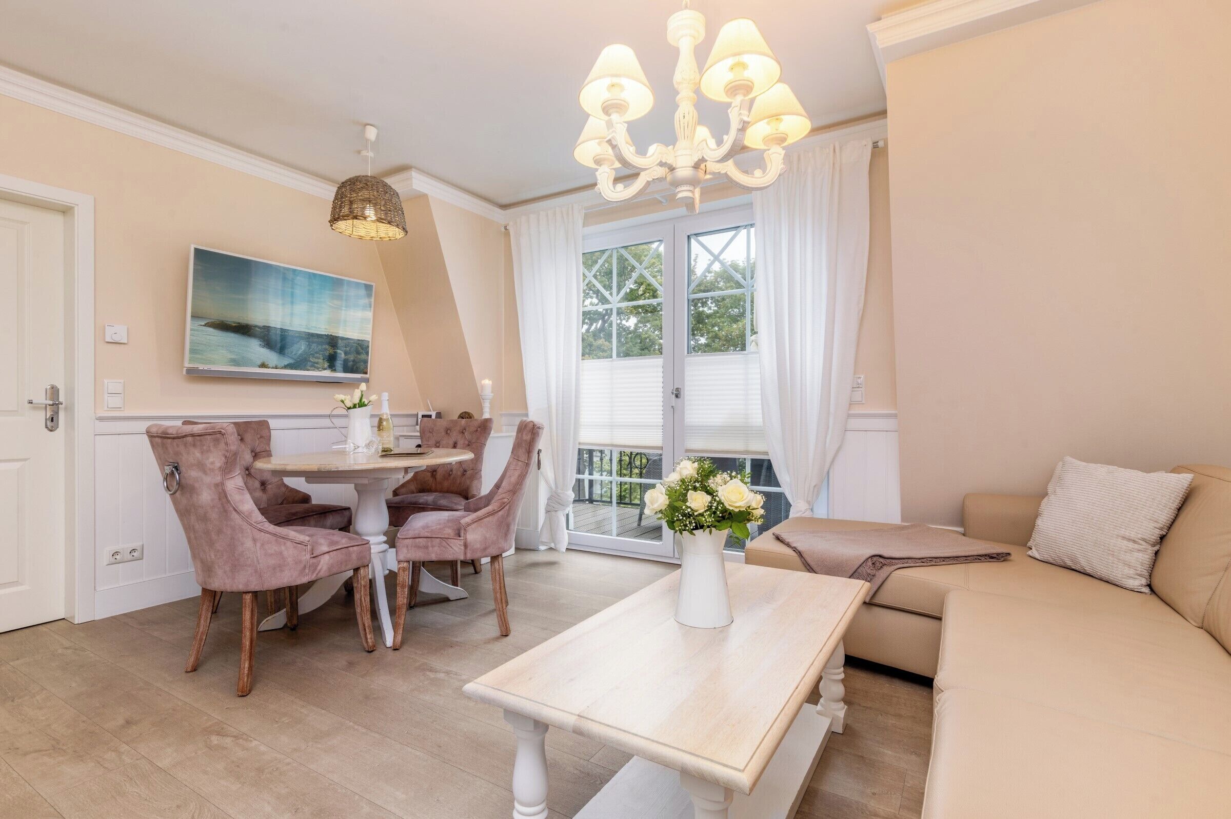 Uma sala de estar moderna com área de jantar, um sofá e um candelabro.