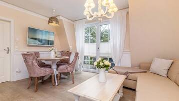 Uma sala de estar moderna com área de jantar, um sofá e um candelabro.