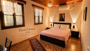 Quarto com cama, mesas de cabeceira, tapete e parede com texto.