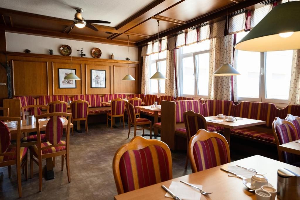 Um restaurante com cabines e mesas, painéis de madeira e luminárias pendentes.