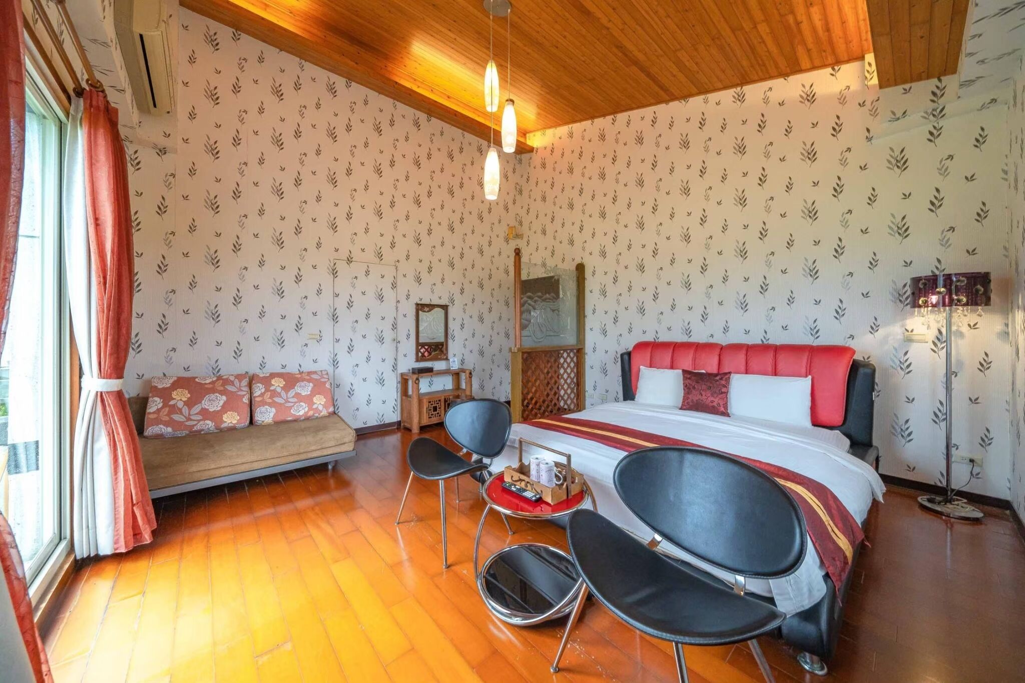 Quarto com cama, sofá, duas cadeiras, mesa pequena e abajur.