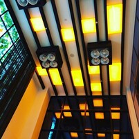 Interior moderno com design de teto geométrico e iluminação embutida.