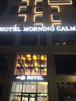Placa de hotel com a inscrição 'HOTEL MORNING CALM' iluminada.
