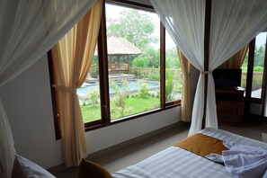 Quarto com uma janela grande, uma cama, uma TV e vista para uma piscina e jardim.