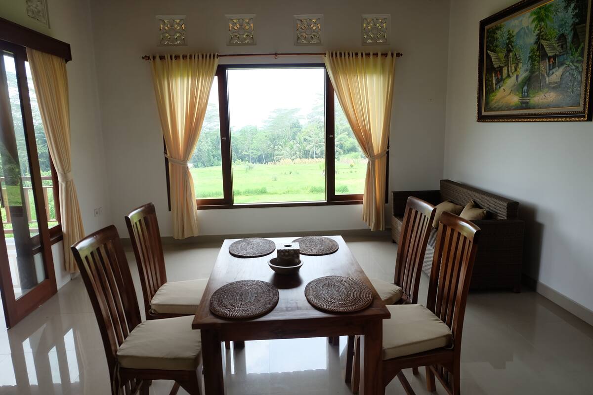 Uma área de refeições com mesa de madeira, quatro cadeiras e um banco.
