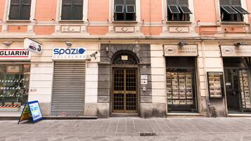 Fachada de edifício com uma loja fechada chamada "500ZI CELLULAR" e outra chamada "PROGETTO IMMOBILIARE".