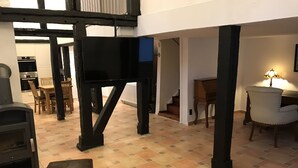 Uma sala de estar com lareira, uma área de refei ções e uma escada que leva a outro andar.