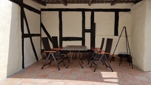 Um pátio com mesa e cadeiras, luminária pendente e vigas de madeira aparente.