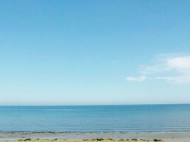 Uma praia com céu claro e águas calmas.