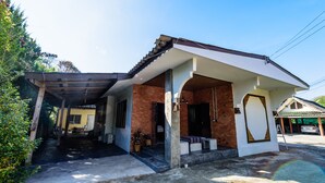 Uma casa de dois andares com varanda coberta, fachada de tijolo e porta branca.