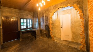 Quarto rústico com paredes de tijolo aparente, teto de madeira e um banco.