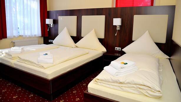 Quarto de hotel com duas camas, cada uma com roupas de cama e toalhas impecáveis.
