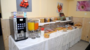 Mesa de buffet com máquina de café, diversos recipientes de comida e uma saladeira.
