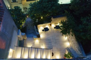 Escadaria de pedra que leva a um terraço no telhado, com área de estar ao ar livre e iluminação suave.