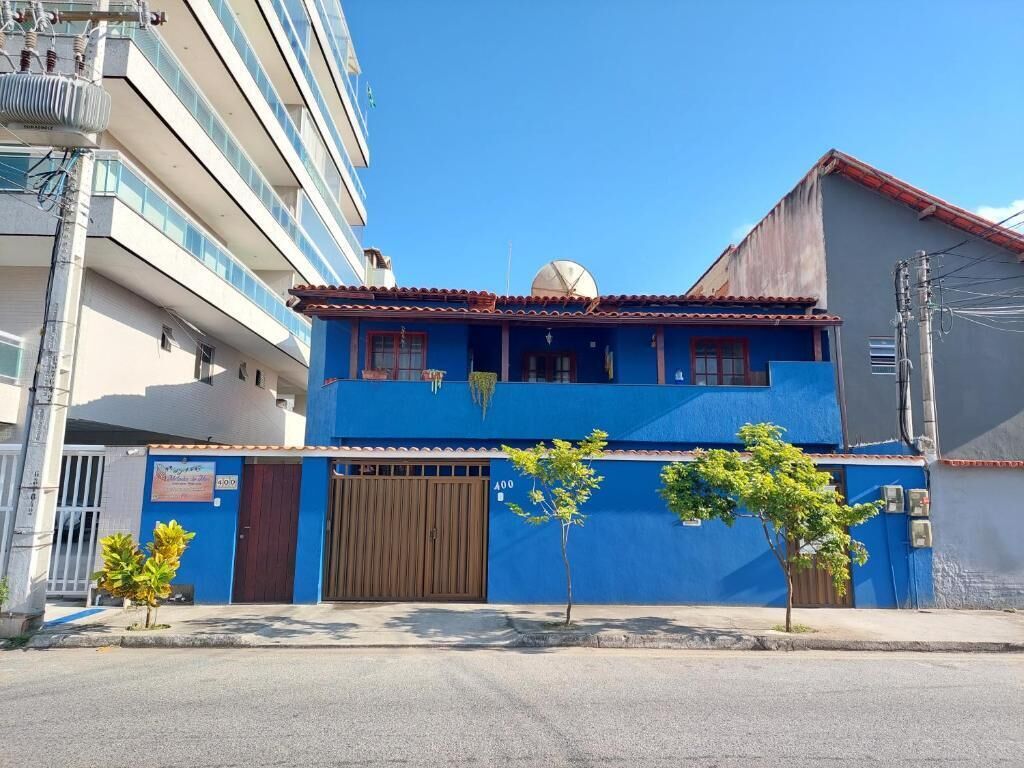 Um edifício de dois andares com fachada azul, portão marrom e antena parabólica no telhado.
