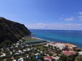 Uma área costeira com uma fileira de veículos recreativos e alguns edifícios perto da praia.