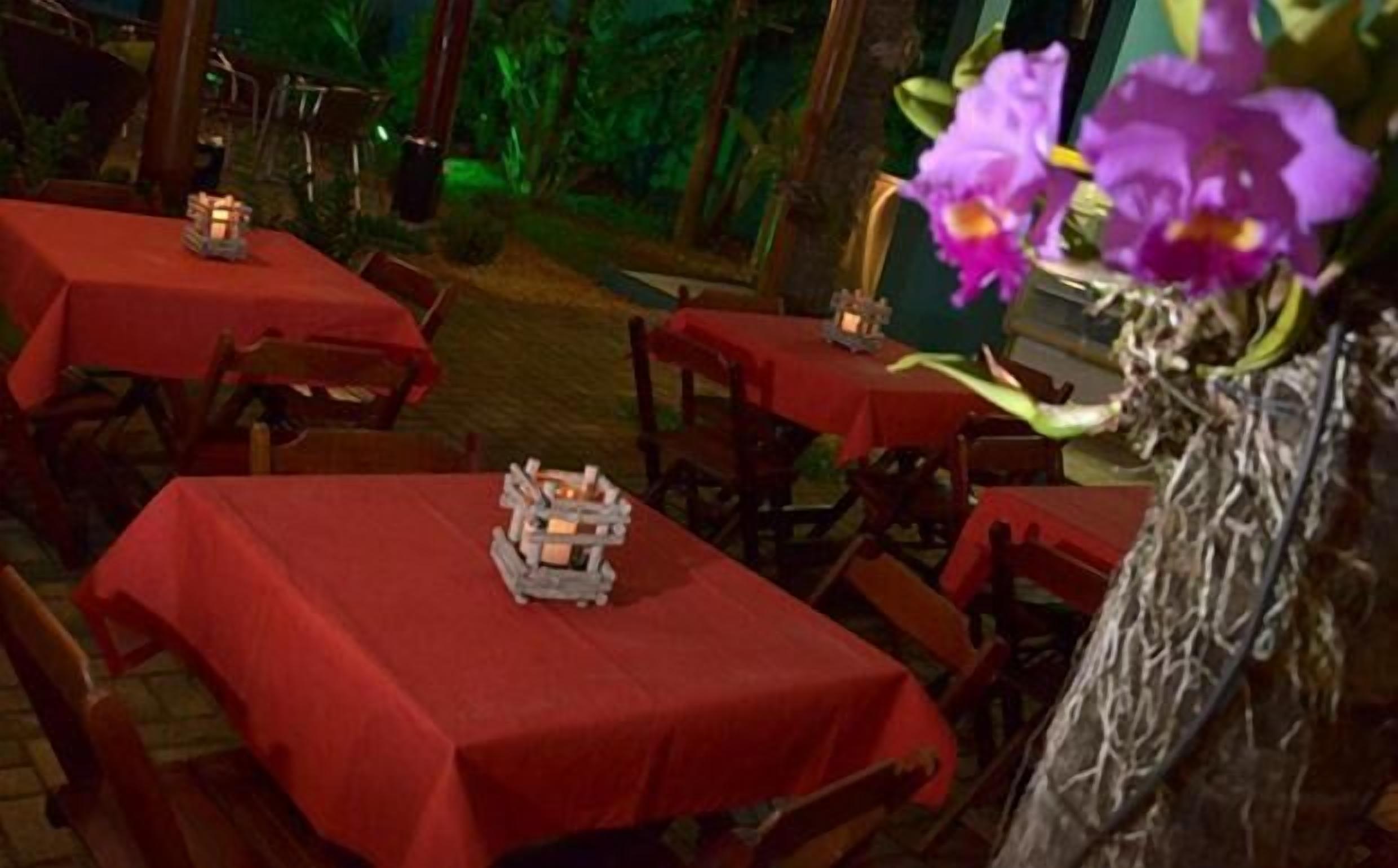 Um restaurante com mesas cobertas por toalhas vermelhas e velas.