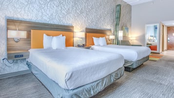 Quarto de hotel com duas camas, cada uma com cabeceira de madeira e mesa de cabeceira.