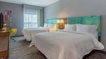 Quarto de hotel com duas camas, uma escrivaninha, uma cadeira e uma televisão.