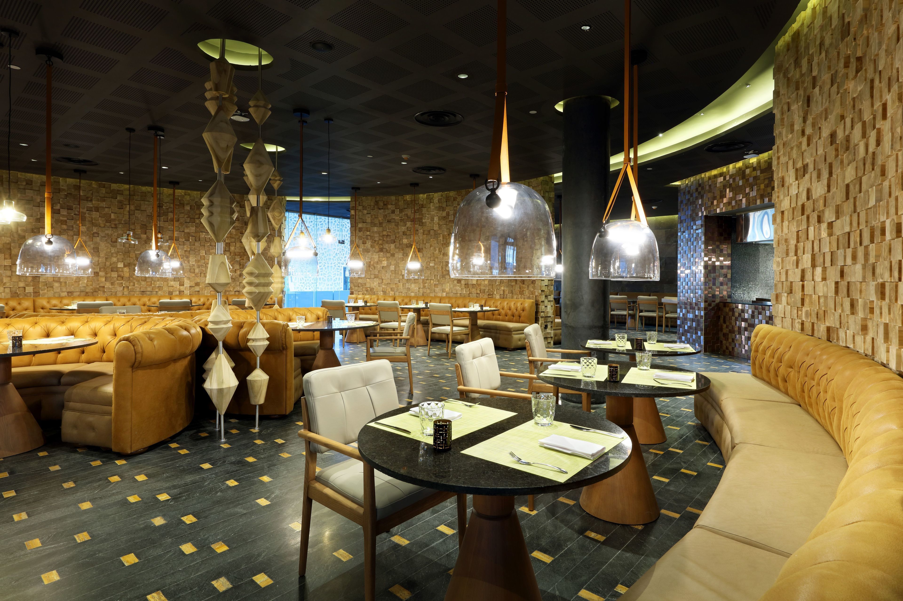 Um restaurante moderno com assentos de couro, luminárias pendentes e piso estampado.