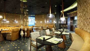 Um restaurante moderno com assentos de couro, luminárias pendentes e piso estampado.