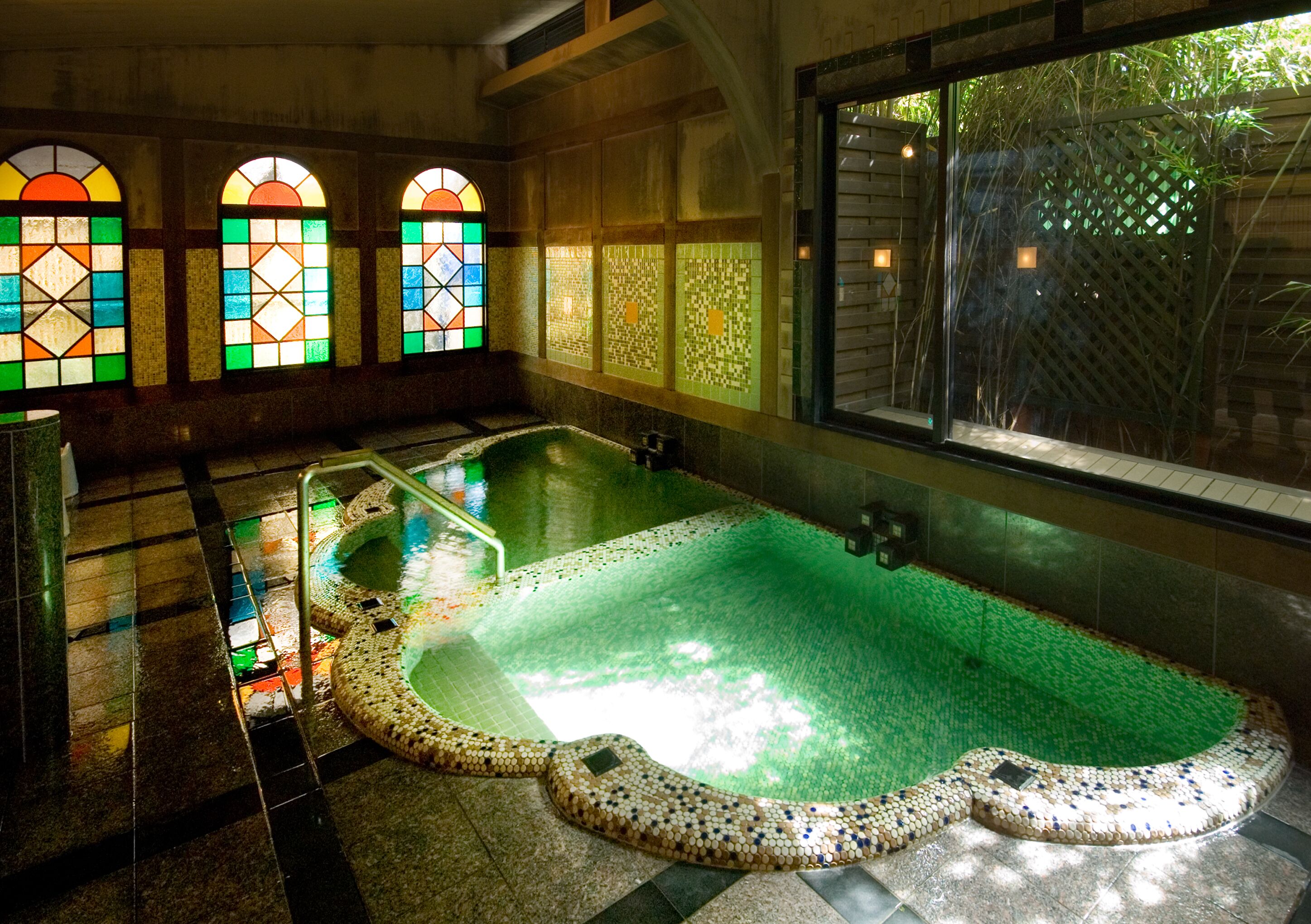 Uma banheira de hidromassagem com mosaicos, piso cerâmico e janelas de vitrais.