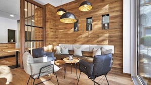 Um interior moderno com paredes de madeira, um sofá, duas poltronas, uma mesa de centro e iluminação pendente.