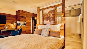 Quarto moderno com uma cama grande, paredes de madeira, escrivaninha e área de chuveiro.