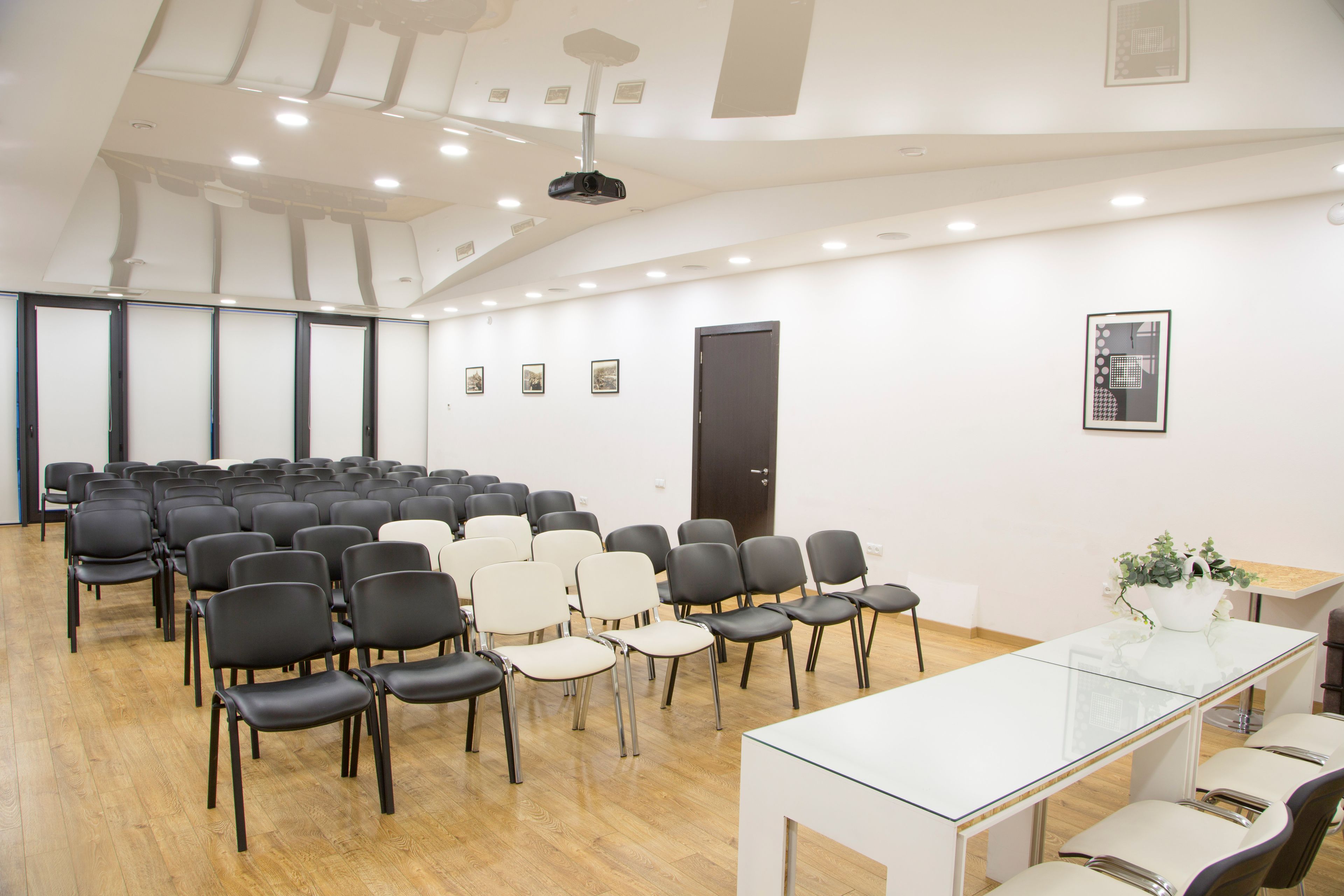 Uma sala de conferência com fileiras de cadeiras, uma mesa de vidro e uma porta.