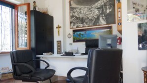 Um quarto com duas cadeiras de escritório pretas, uma escrivaninha com computador e uma janela com detalhes em ferro ornamental.