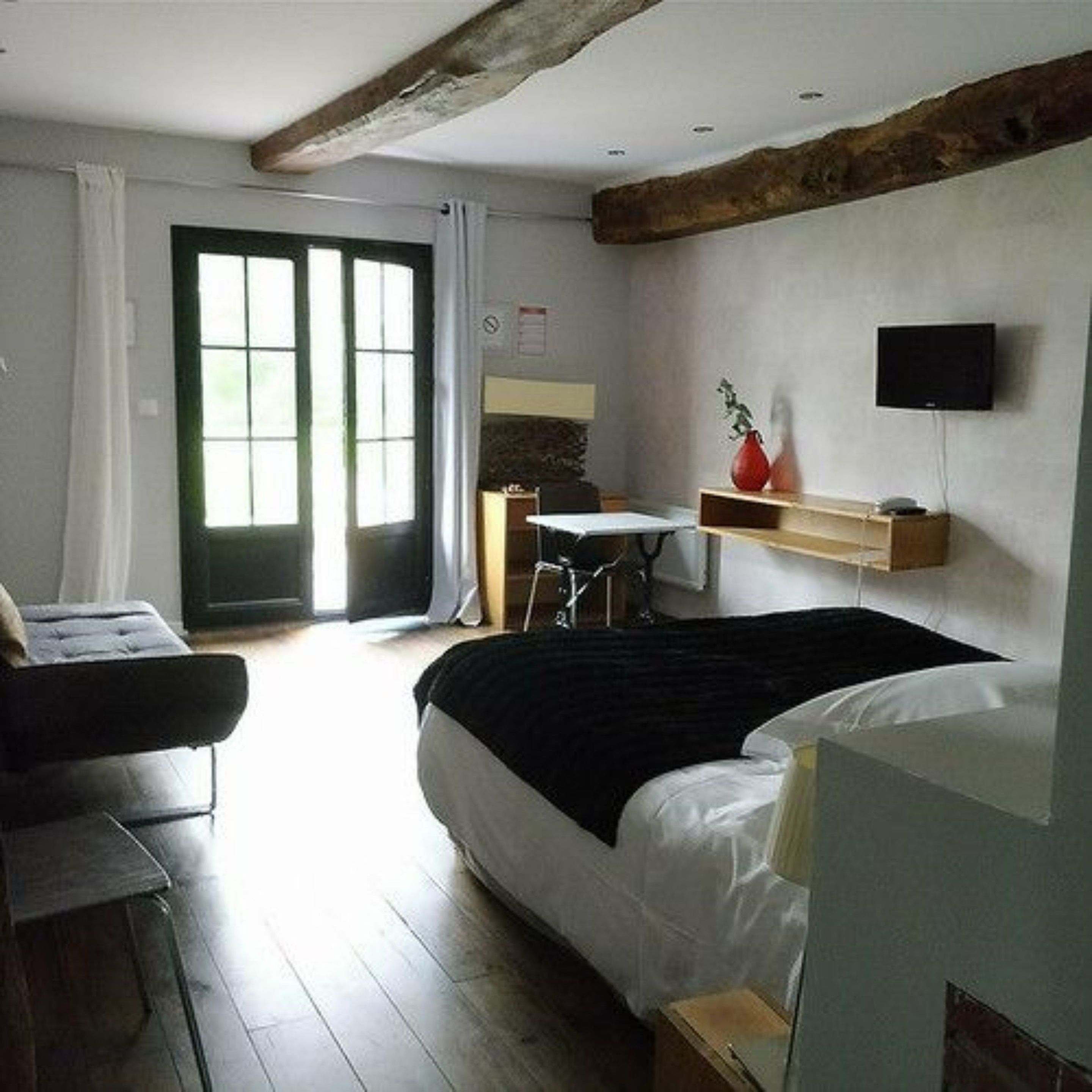 Quarto com uma cama, escrivaninha e televisão.