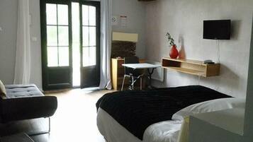 Quarto com uma cama, escrivaninha e televisão.