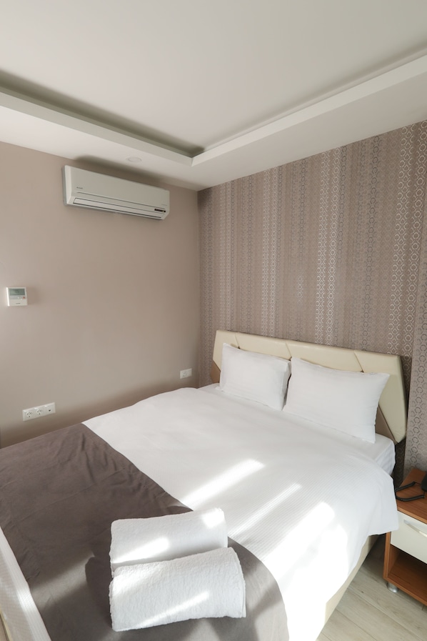 Quarto de hotel com cama grande, mesa de cabeceira, ar condicionado e parede estampada.