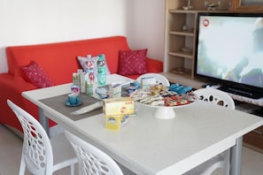 Uma sala de jantar com uma mesa posta para dois, exibindo diversos alimentos e bebidas.