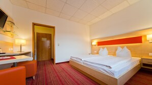 Quarto de hotel com cama, escrivaninha e cadeira.