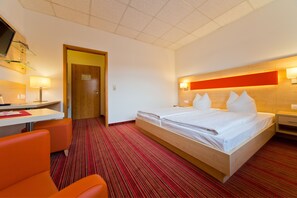 Quarto de hotel com cama, escrivaninha e cadeira.