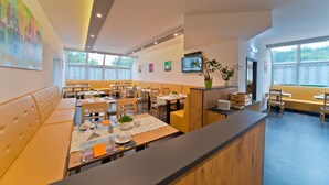 Um restaurante moderno com um balcão extenso, diversas áreas de estar e grandes janelas.