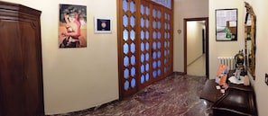 Um corredor com um armário de madeira, uma obra de arte emoldurada, um mural de avisos e um espelho decorativo.