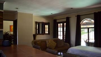Quarto com cama, sofá, mesa de jantar e janela com cortinas.