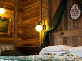 Um quarto em estilo cabana de madeira, com uma cama, um quadro emoldurado e um aplique de parede.